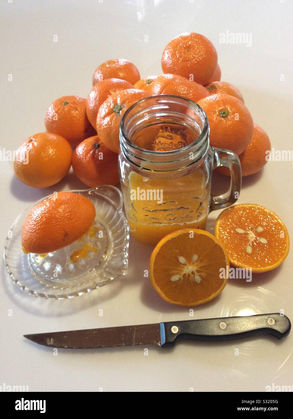 Citrus glass juicer with juice in glass and clementines on white ...