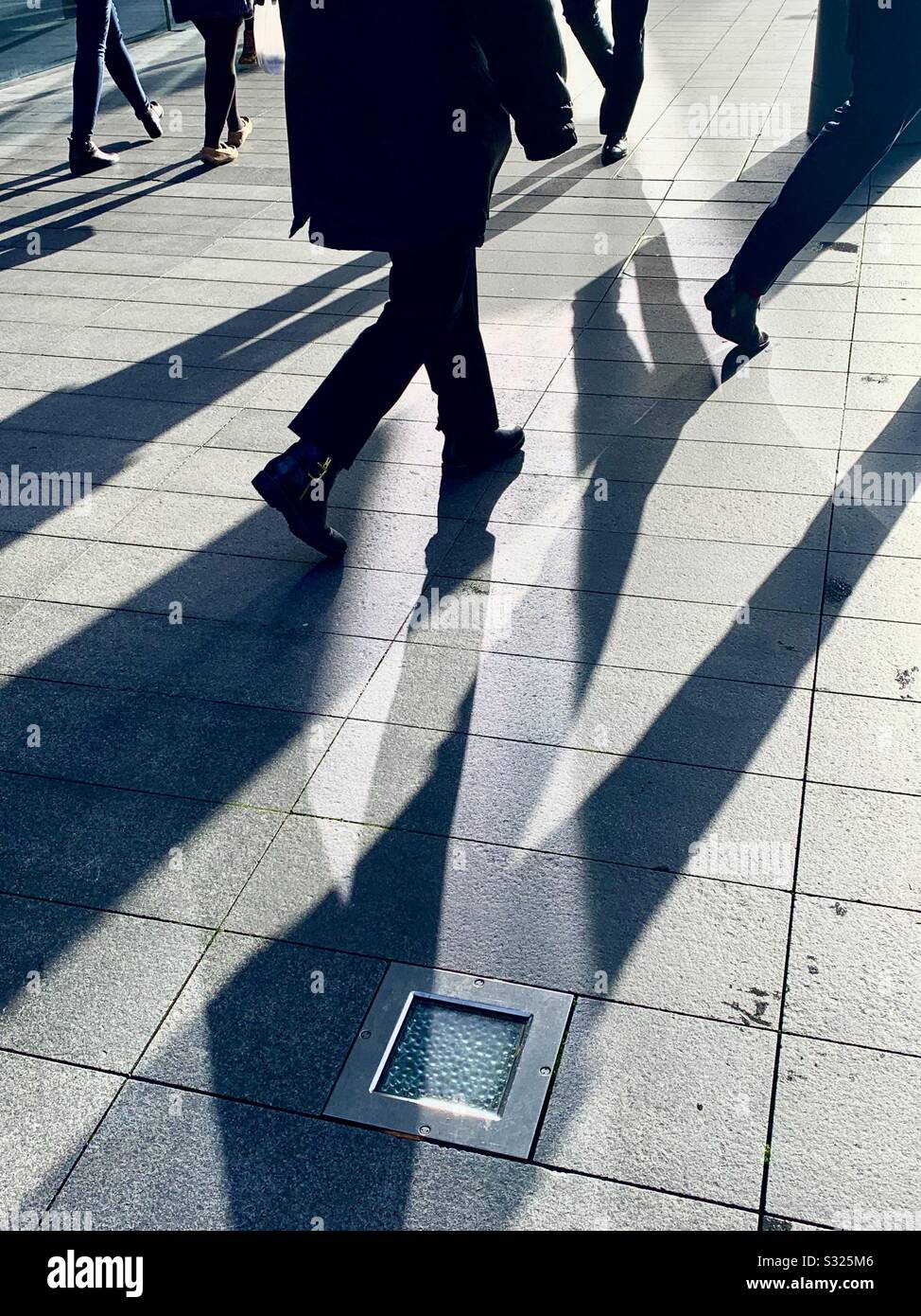 Commuters with long shadows on the pavement in January Stock Photo - Alamy