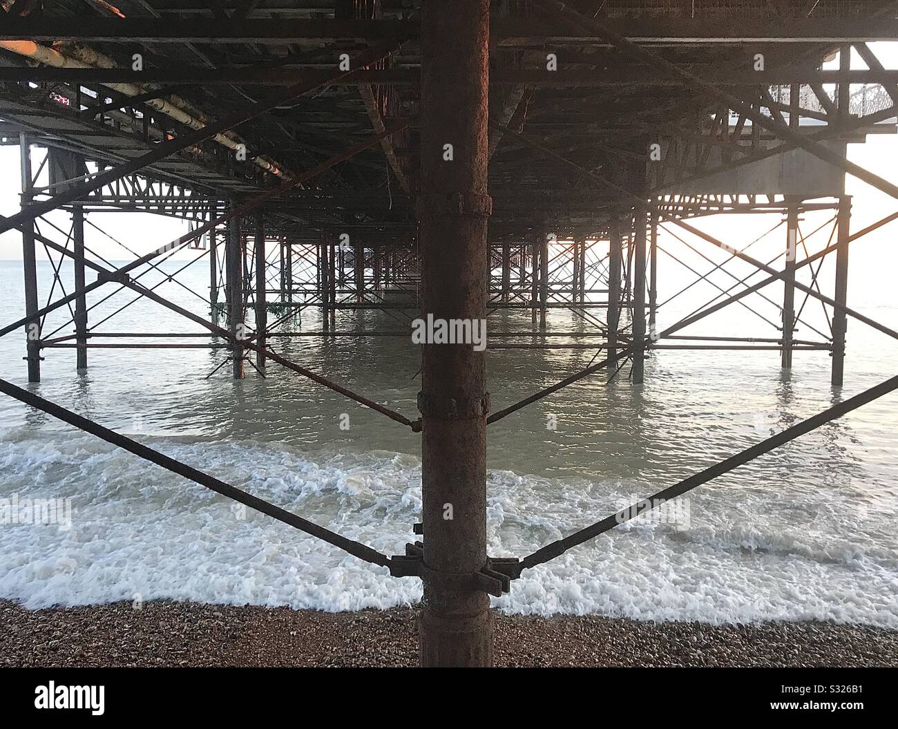 Under Brighton Palace Pier at sunset Stock Photo - Alamy