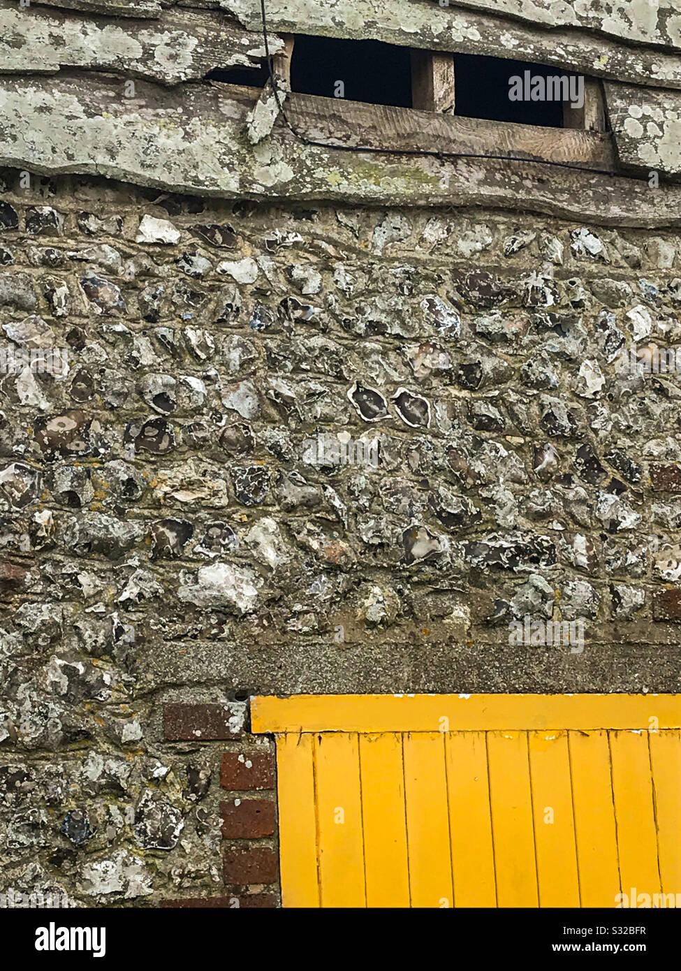 Old flint walled barn with yellow door. England, South Downs Stock ...