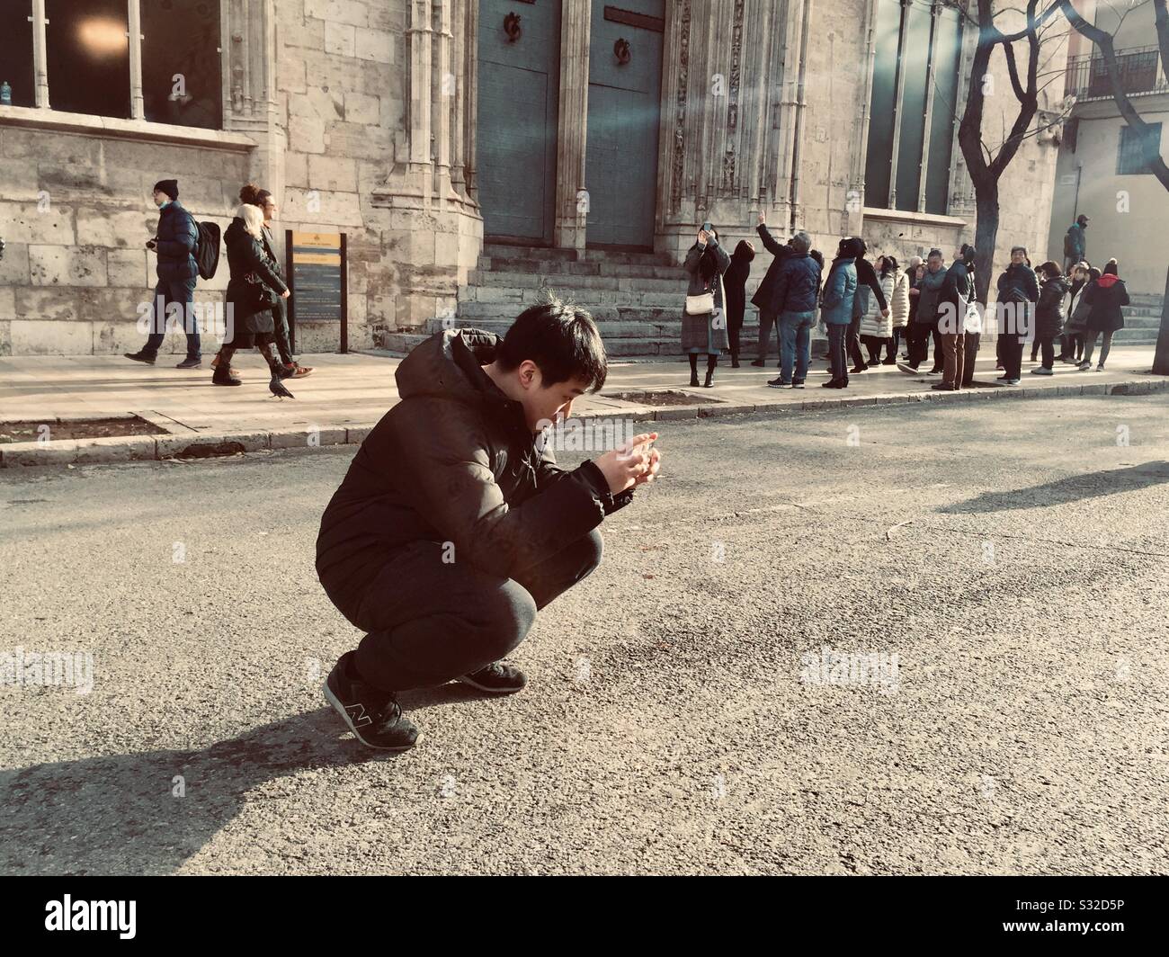 a crouched man taking a picture Stock Photo - Alamy