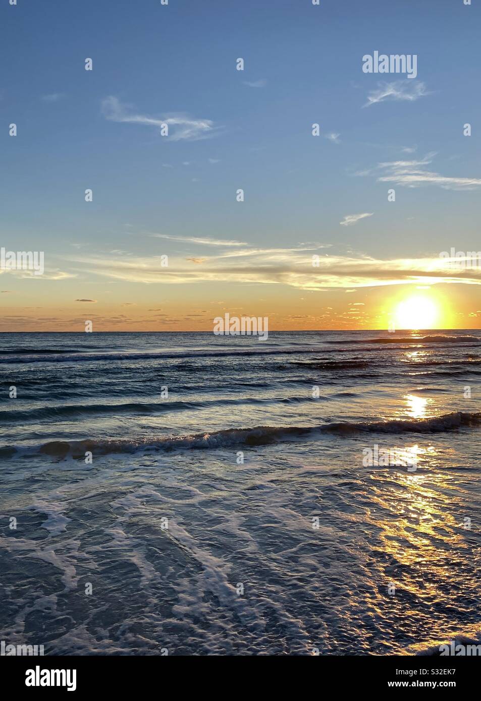 Sunset with sun globe and colorful reflections over Gulf of Mexico ...