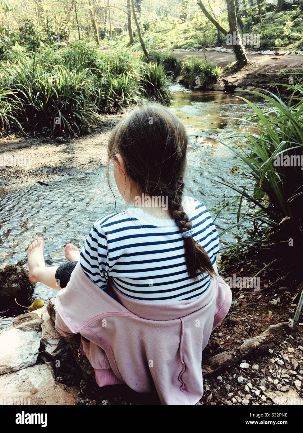 Young girl sitting by stream Stock Photo - Alamy