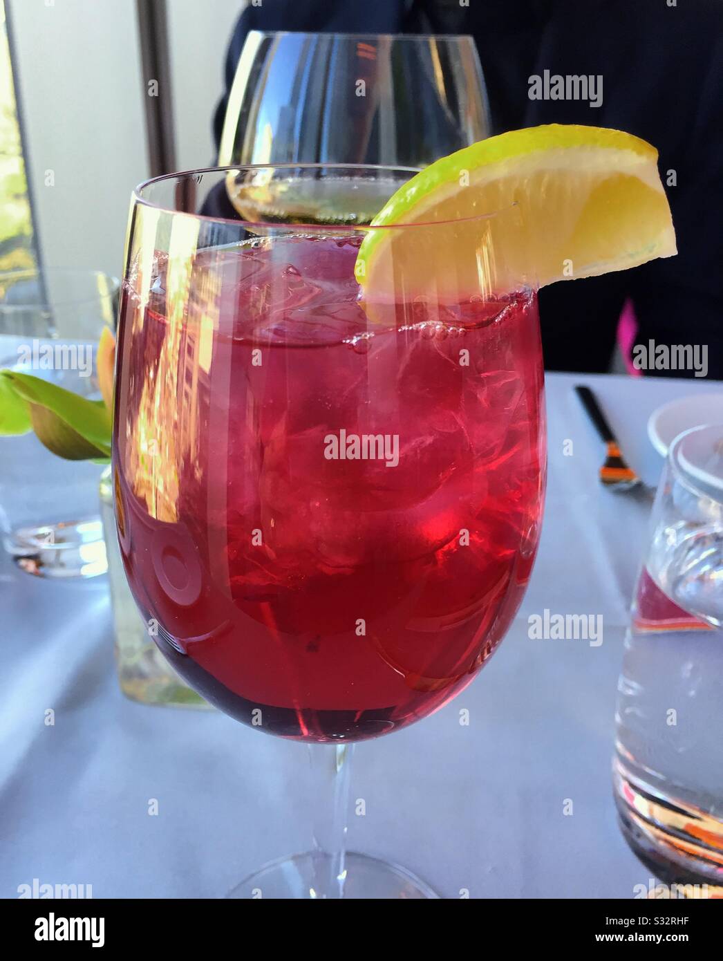 Close up of a scarlet colored fruit infused iced tea with lemon wedge ...