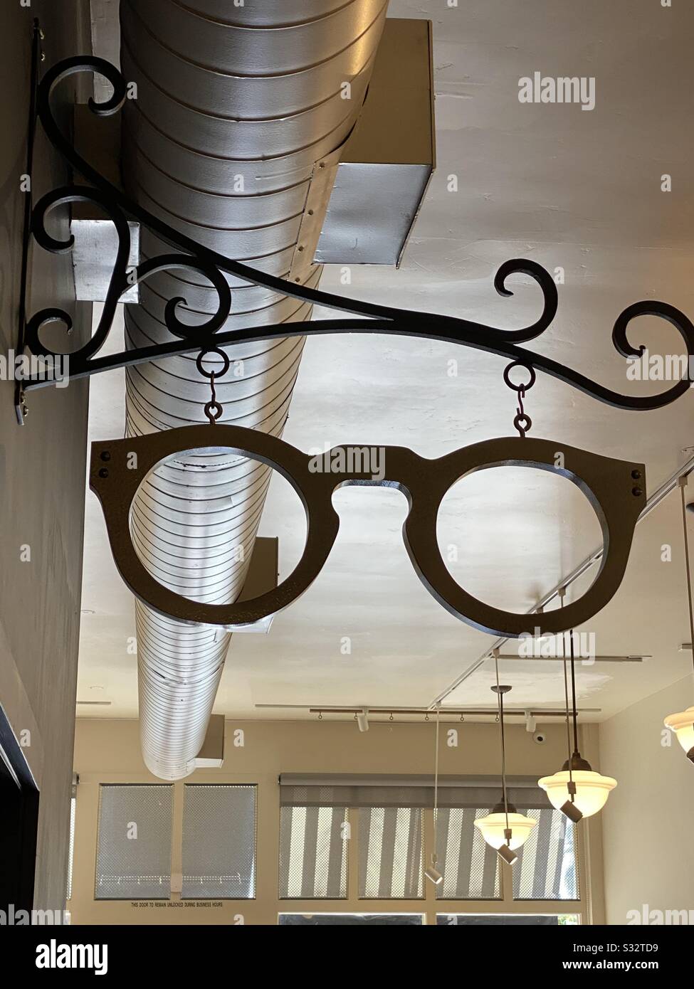 A stylized pair of glasses frames hang from a sign in an optometrist ...