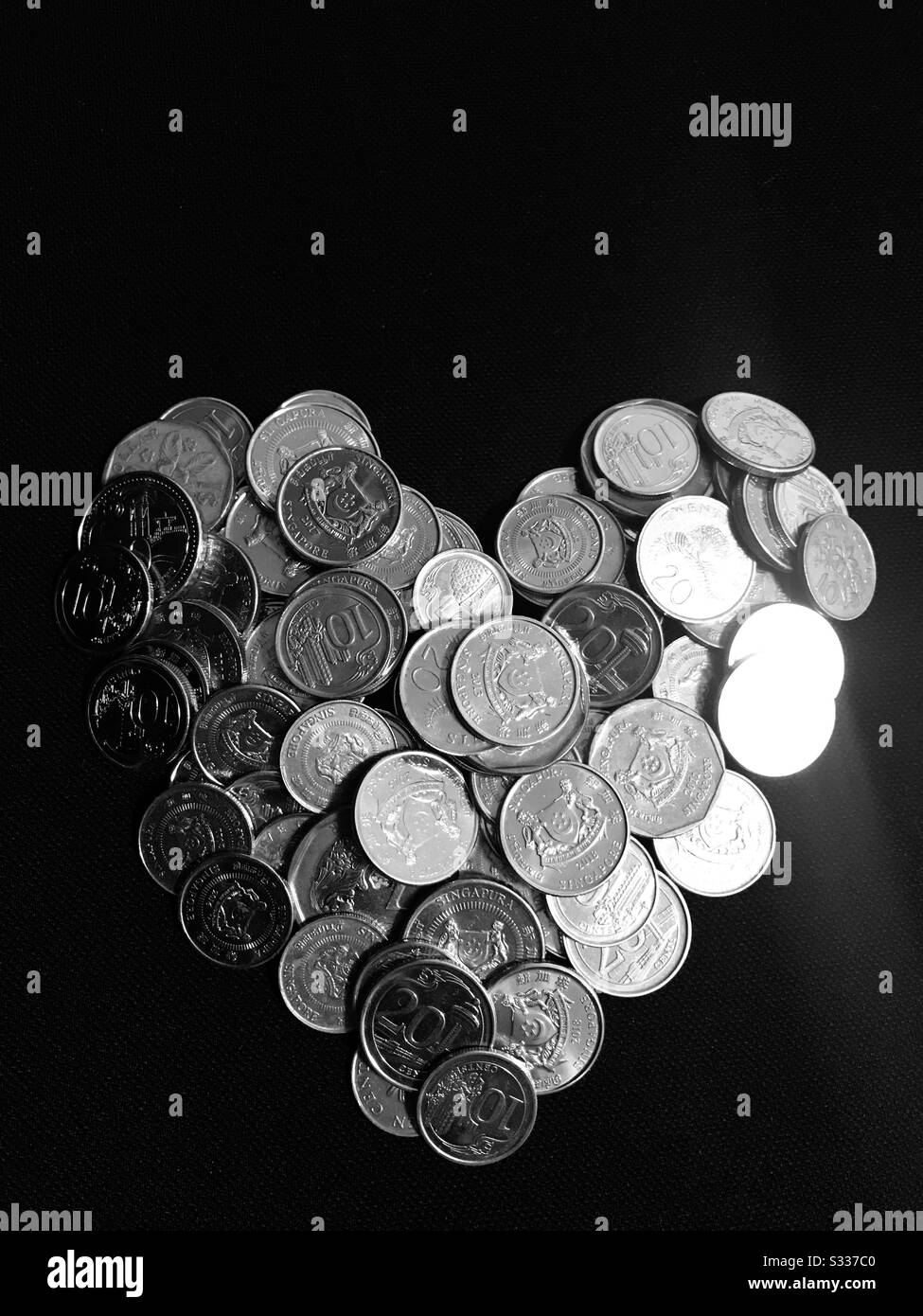 assorted Singapore coins arranged in heart shape in a black background ...
