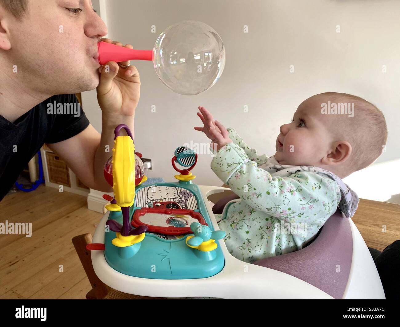 Dad blows bubble for baby Stock Photo - Alamy