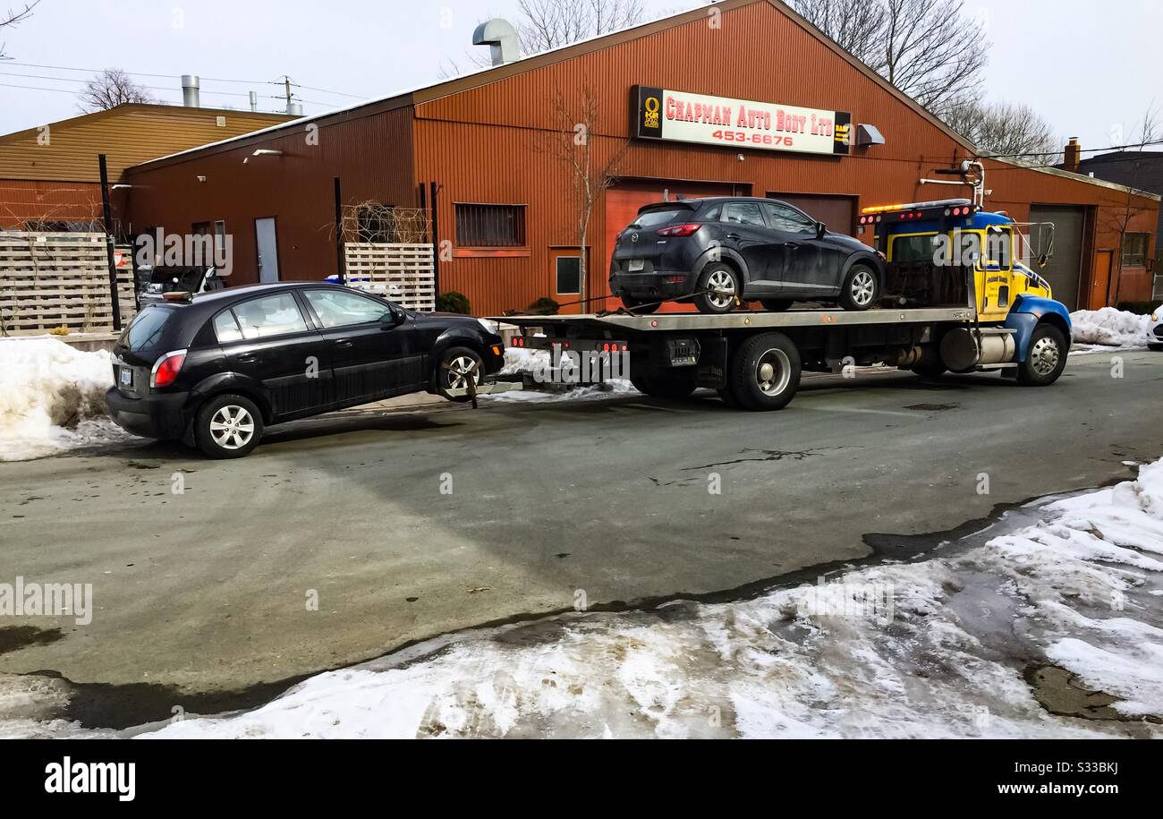 Tow truck with two cars on a city street Stock Photo - Alamy