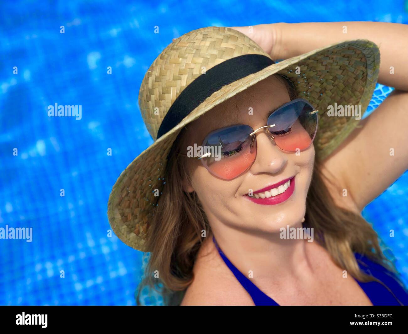 Portrait Of Woman Wearing Blue Bikini Sunglasses And Straw Hat Near