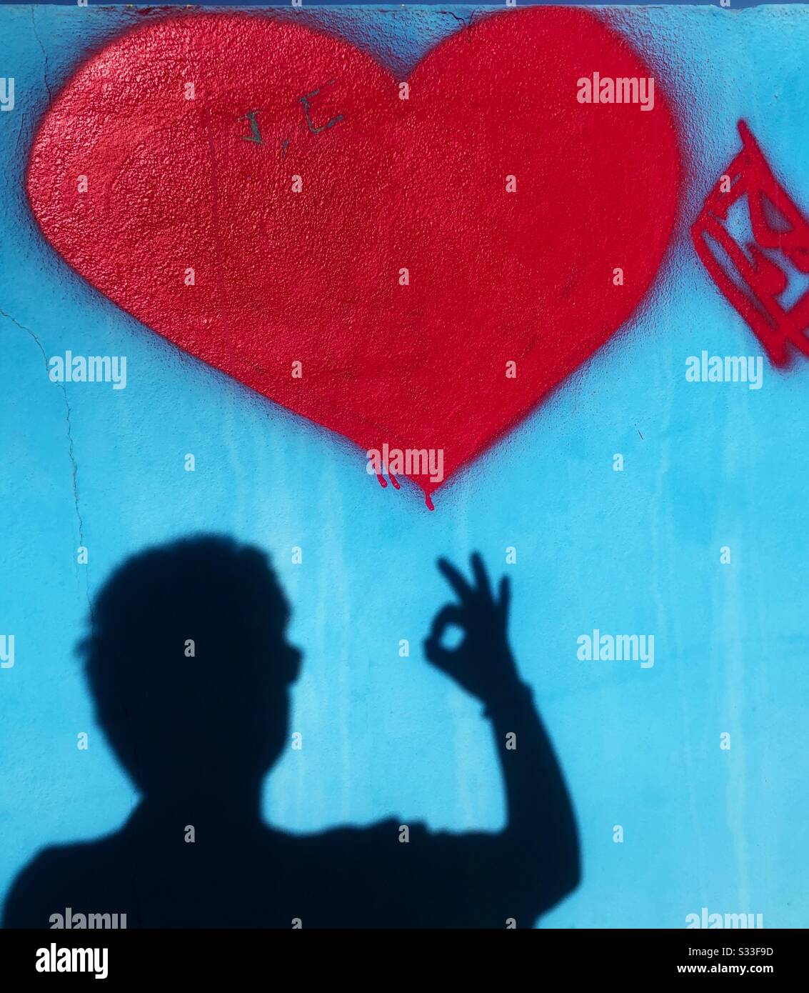 Shadow of woman with OK hand signal with heart graffiti Stock Photo - Alamy
