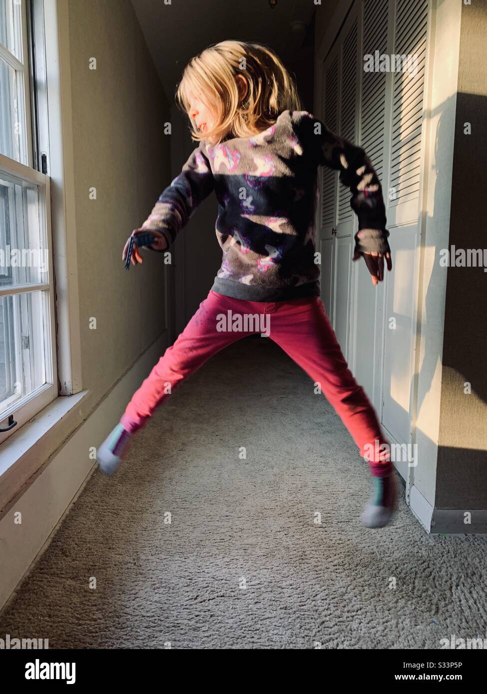Young girl mid jump inside home Stock Photo - Alamy