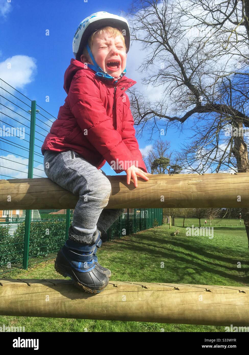 Three year old boy stuck climbing over a fence Stock Photo - Alamy