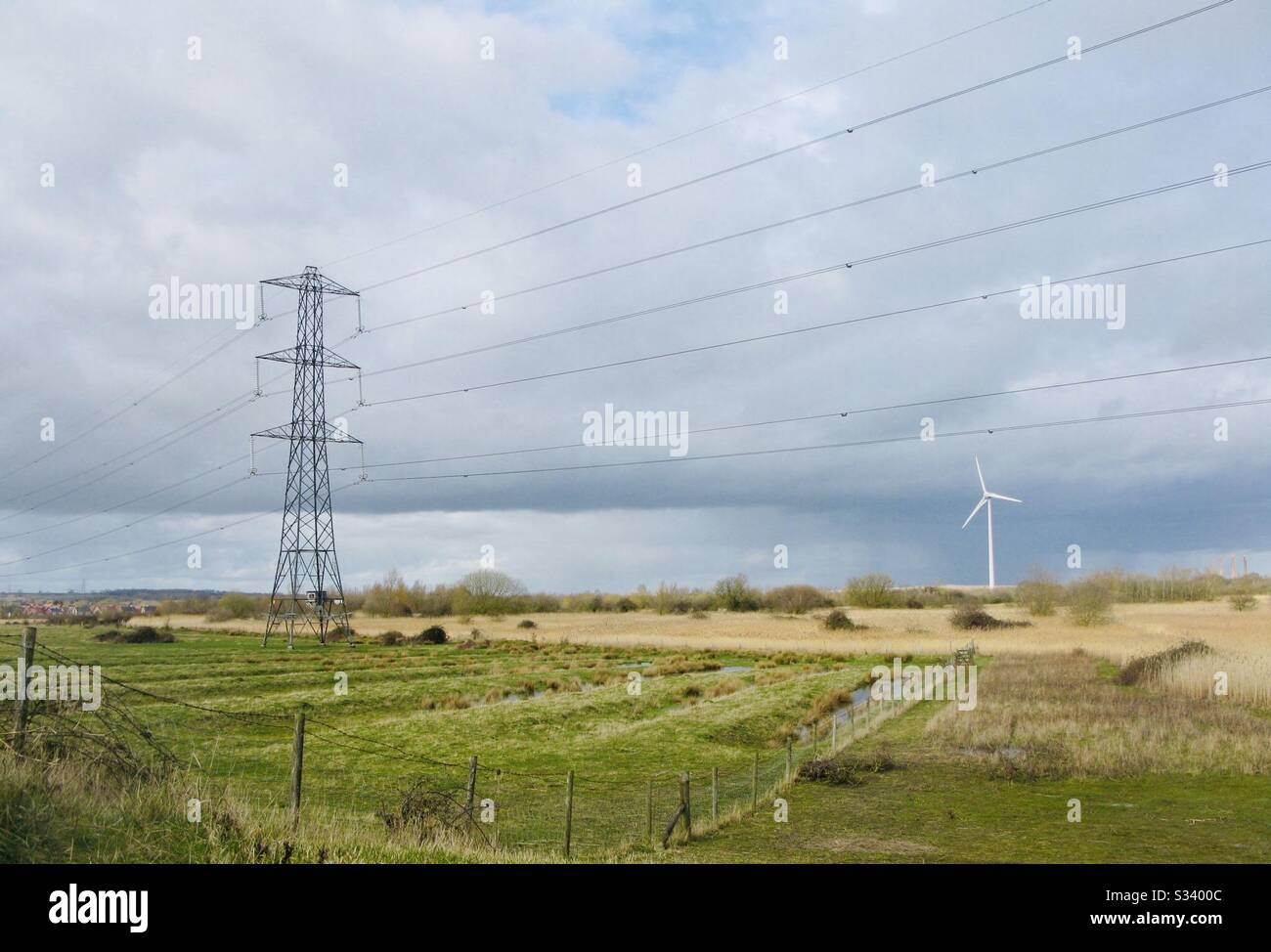 An electric pylon crossing countryside with wind turbine Stock Photo ...
