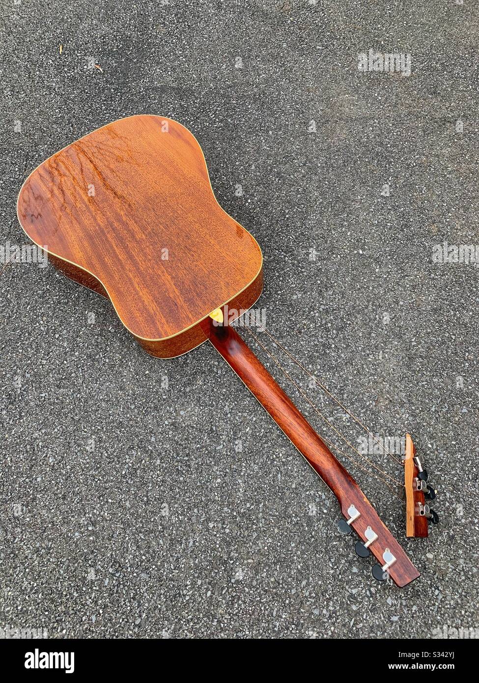 Broken guitar laying on pavement in car park Stock Photo - Alamy