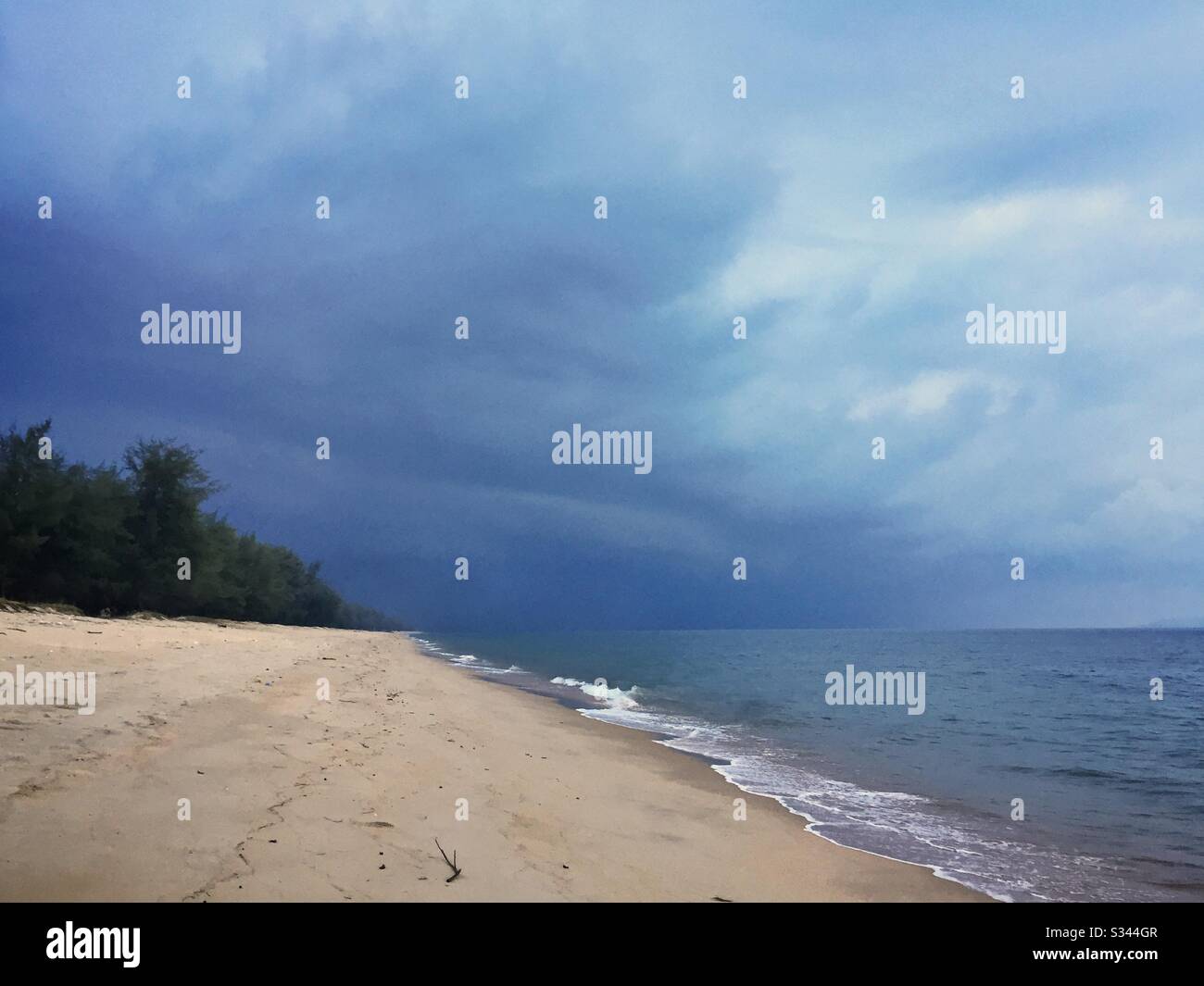 An evening thunderstorm approaches the beach at twilight in Batu Rakit ...