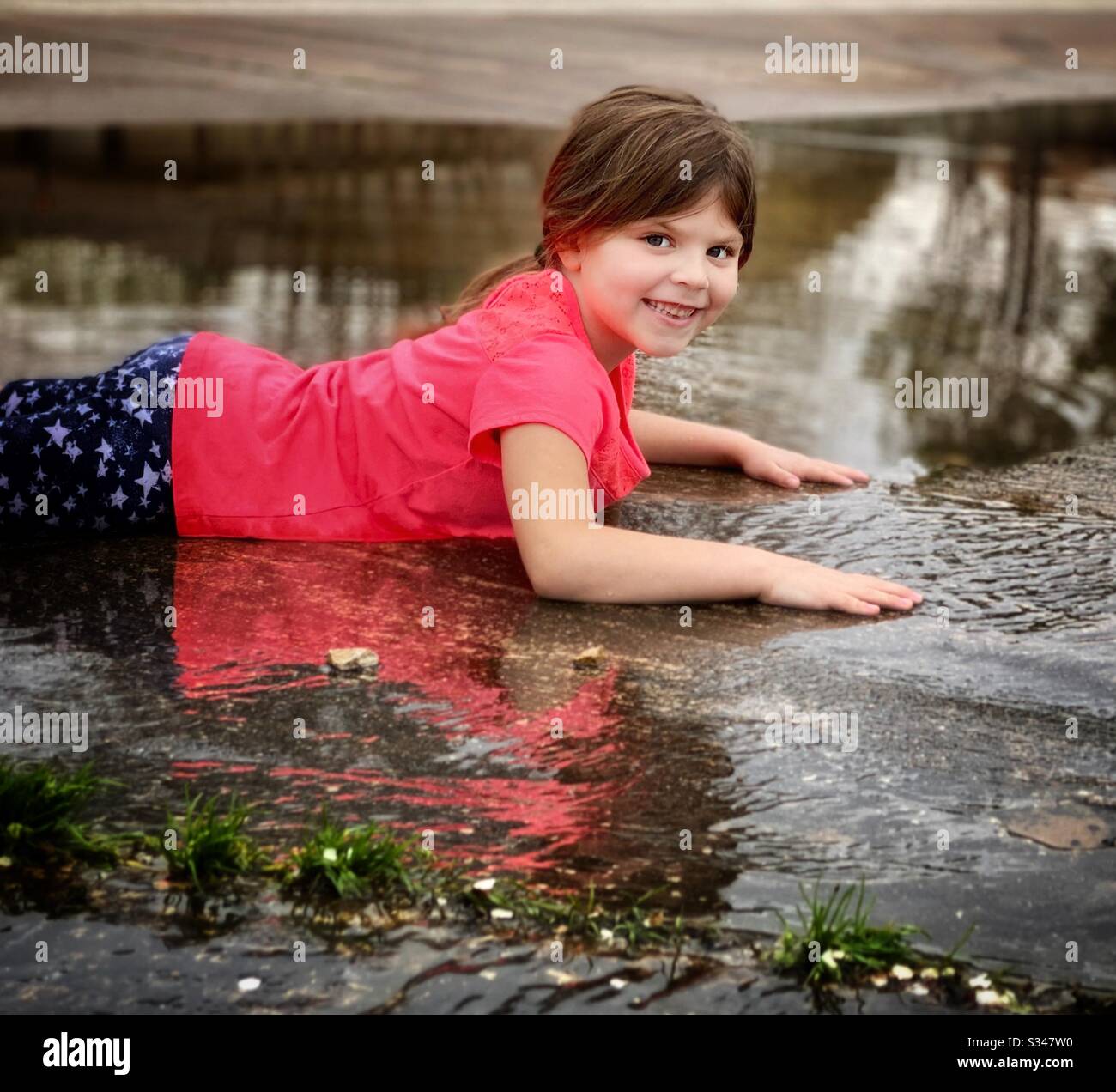 Little girl making big happy smiles while playing in a large rain ...