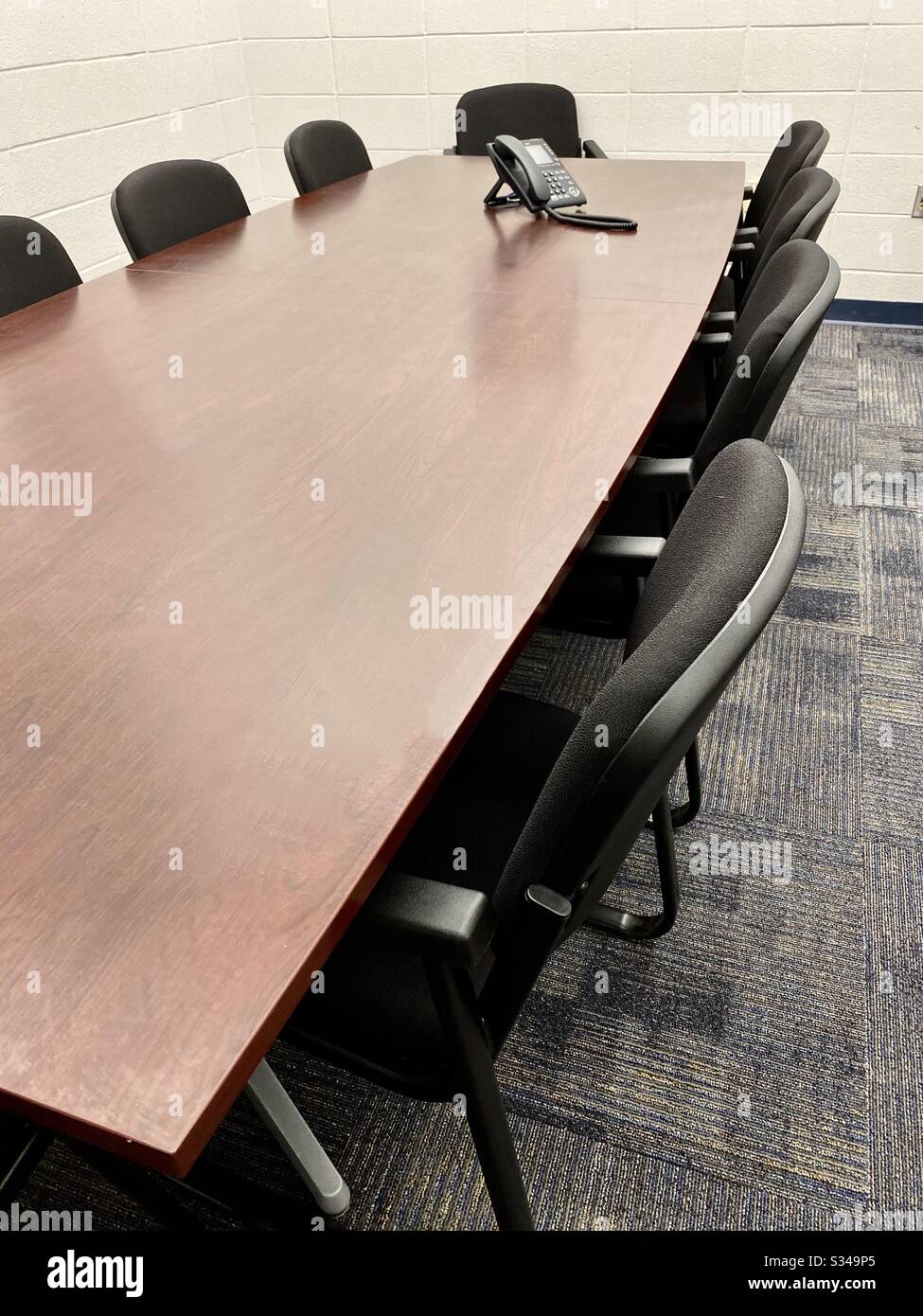 Angle view of a conference room with wood conference table and 10 black ...