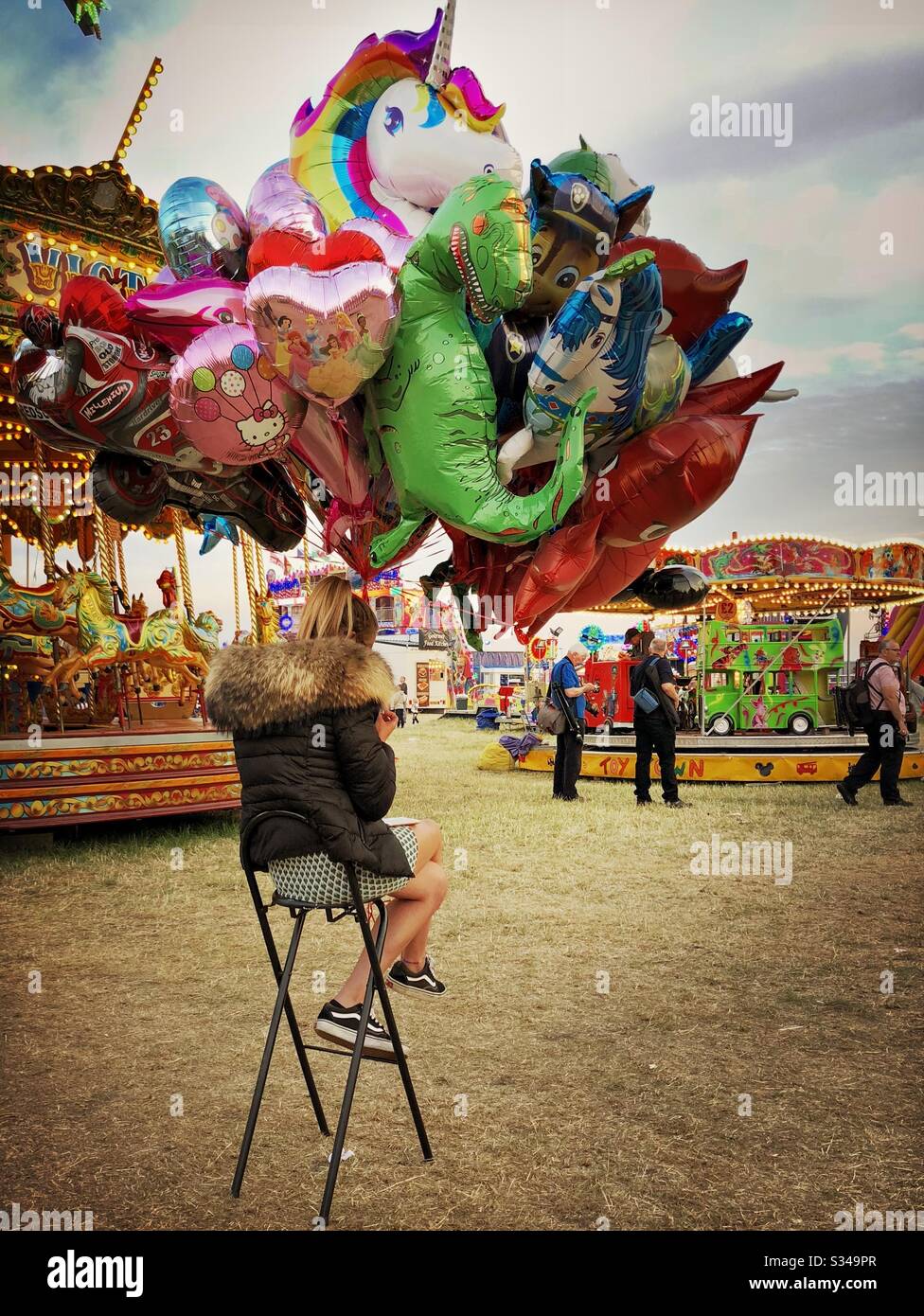 A young girl is seen from behind. Selling and holding helium filled ...