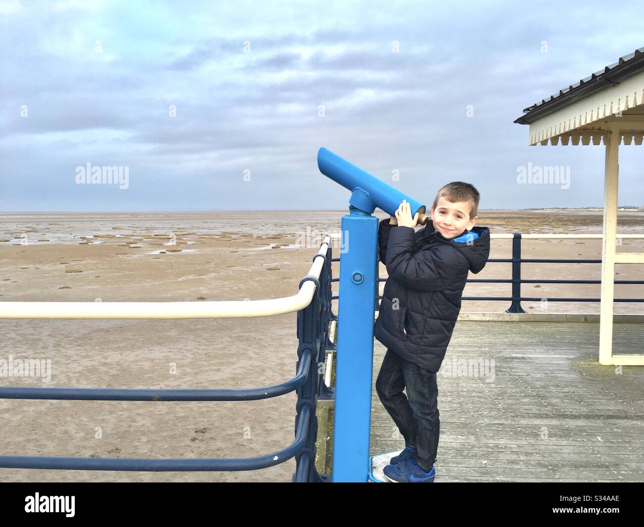 Boy at pier with telescope Stock Photo - Alamy
