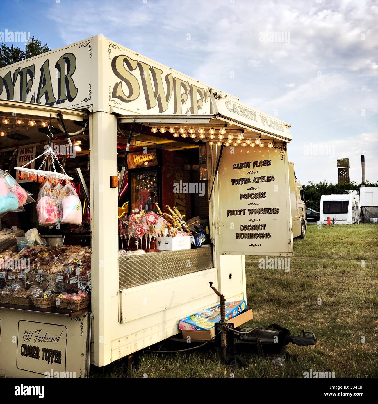 Sweets stall with candy floss at a travelling fairground. Caravans are ...