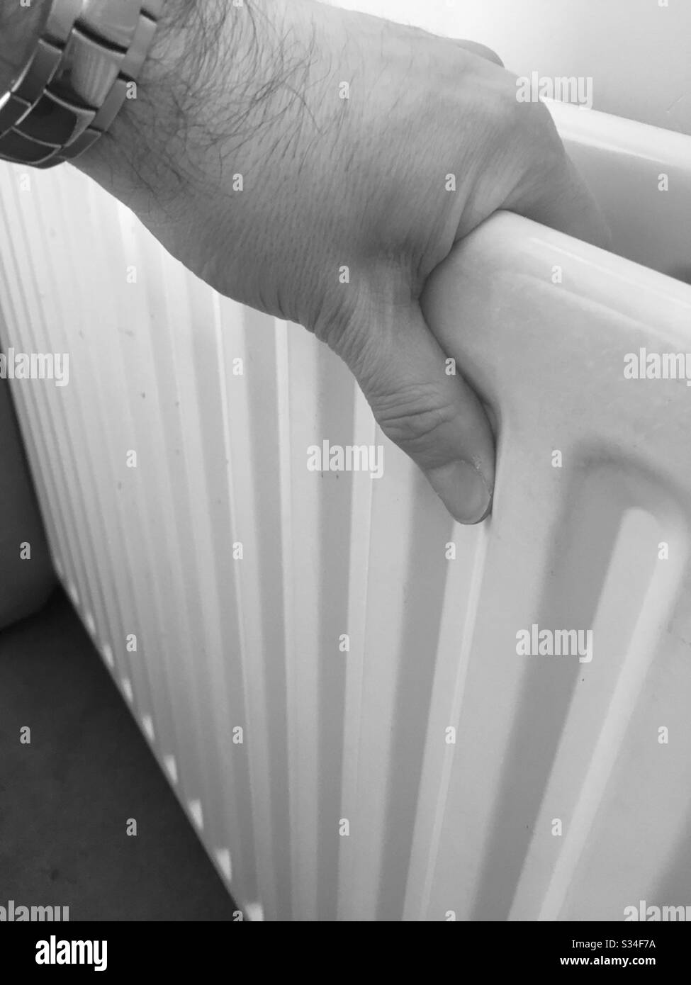 Mans hand touching radiator Stock Photo - Alamy