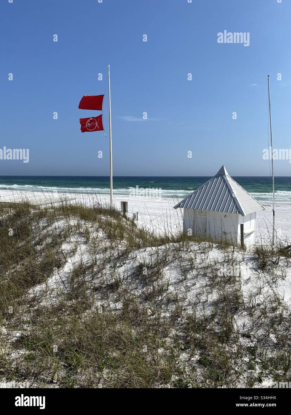Red warning flags flying on white sand beach due to beach closures and ...