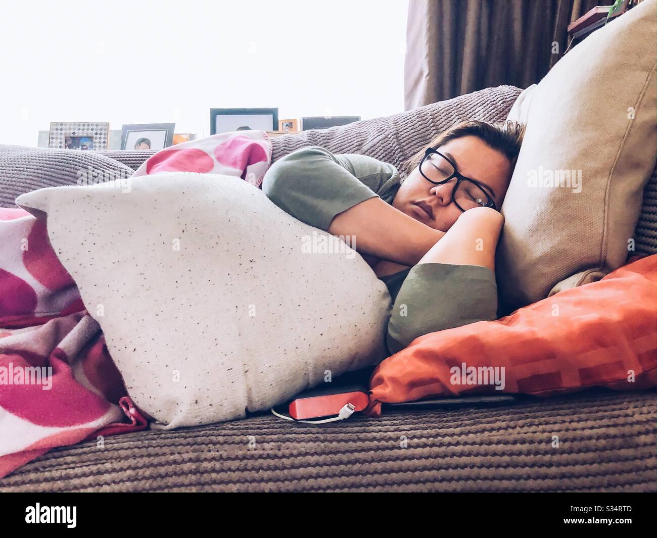 A lady taking a nap on a sofa with cushions and a blanket Stock Photo ...