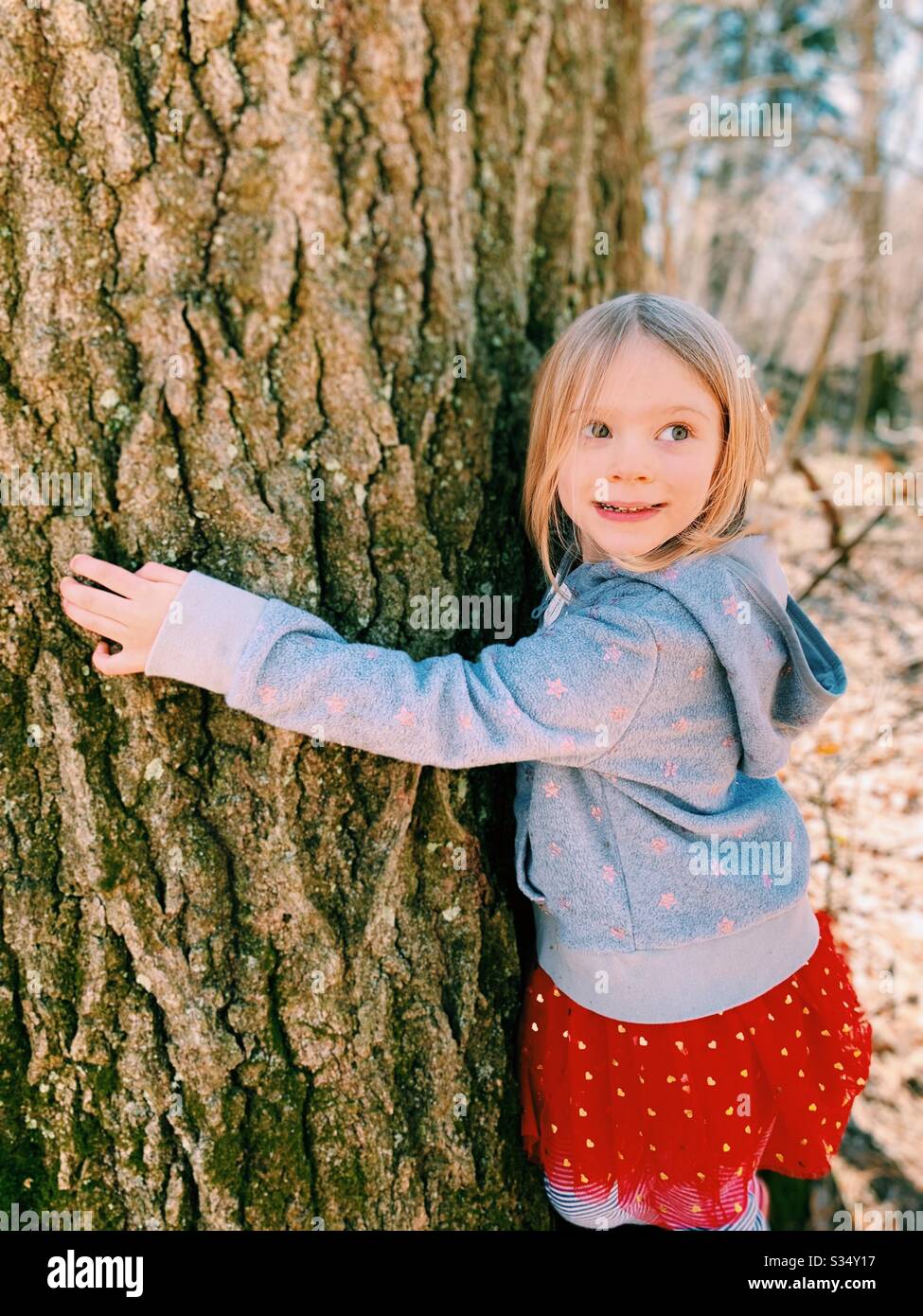 Girl smiling and hugging a tree Stock Photo - Alamy