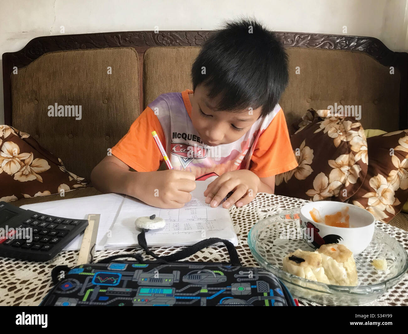 A student do homework assignment on a table with snacks at home during ...