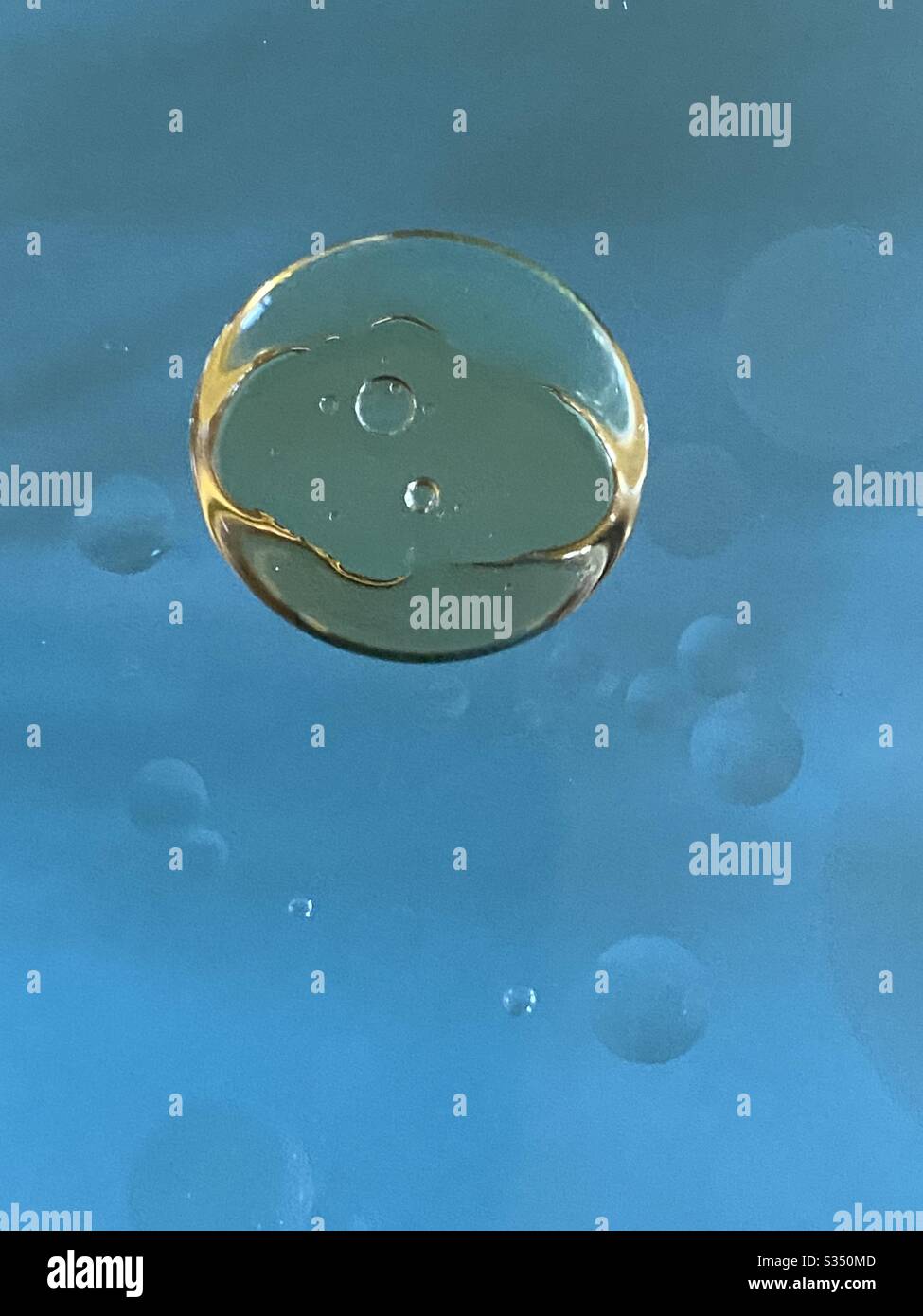 Abstract of a large oil droplet on water with blue background Stock ...