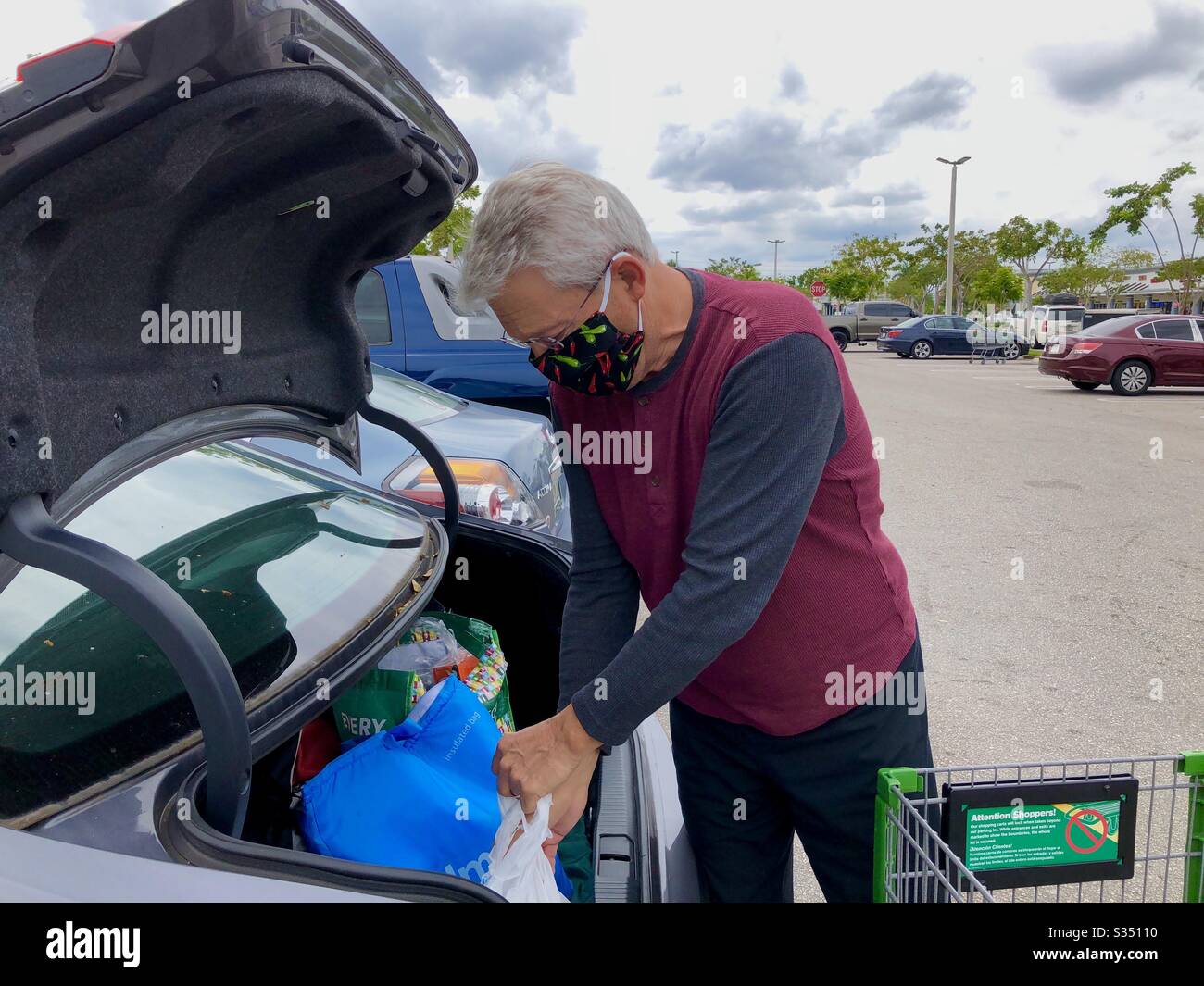 Man loading groceries into his car wearing a home-made mask during the ...