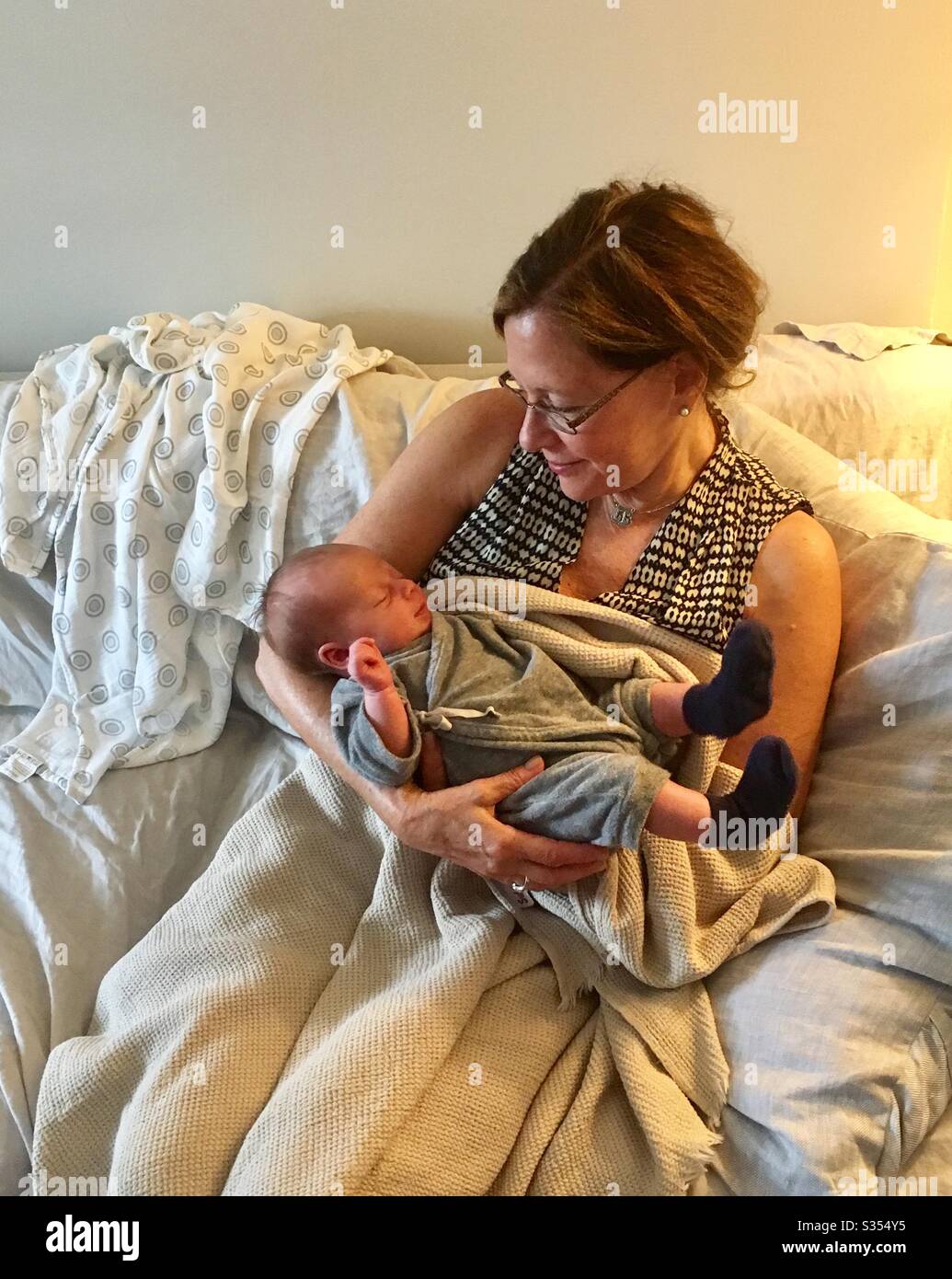 Young grandmother smiling and holding her newborn grandchild in her ...