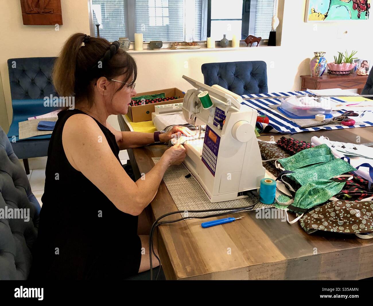 Woman at home volunteering to make non-surgical masks for the community ...