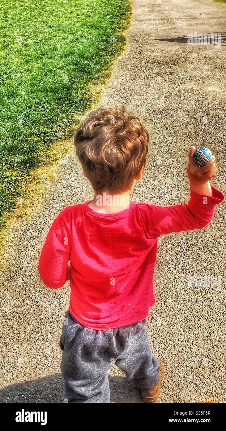 Toddler child boy throwing bouncy ball in the park back view Stock ...