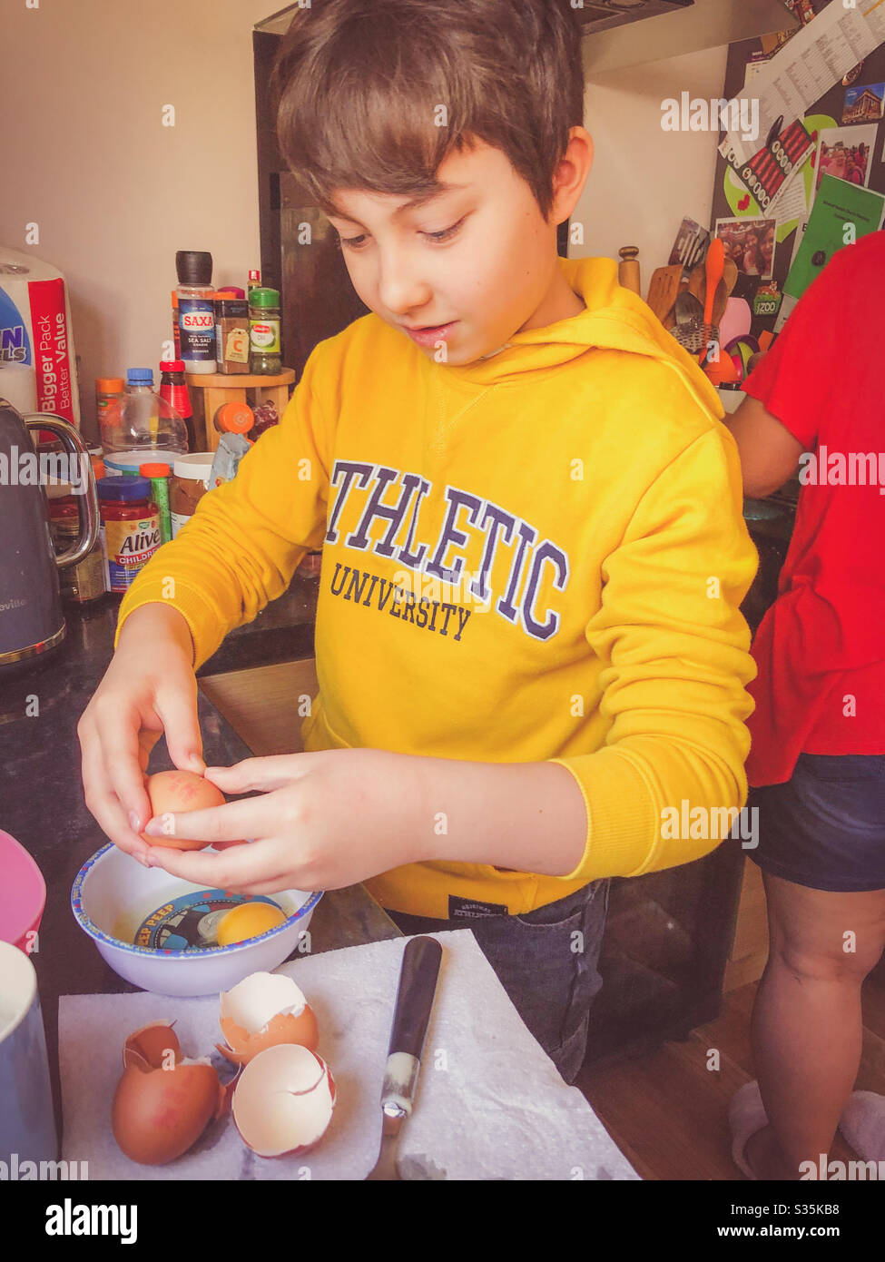 A boy breaking an egg into a plastic bowl Stock Photo - Alamy