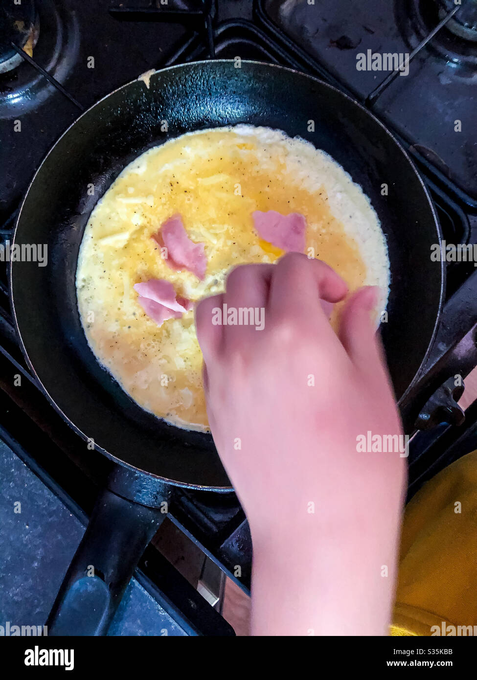 A child’s hand sprinkles ham into an omelette Stock Photo - Alamy