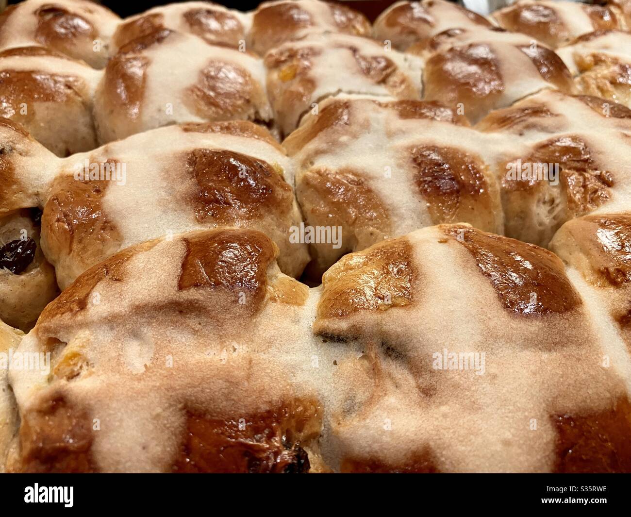 Side view of freshly baked, fruit-filled Hot Cross Buns, cooling on a ...