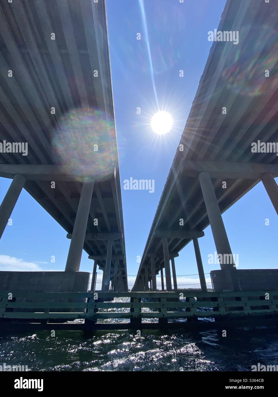 Sun flares passing underneath the Destin, Florida bridge on the Gulf of ...