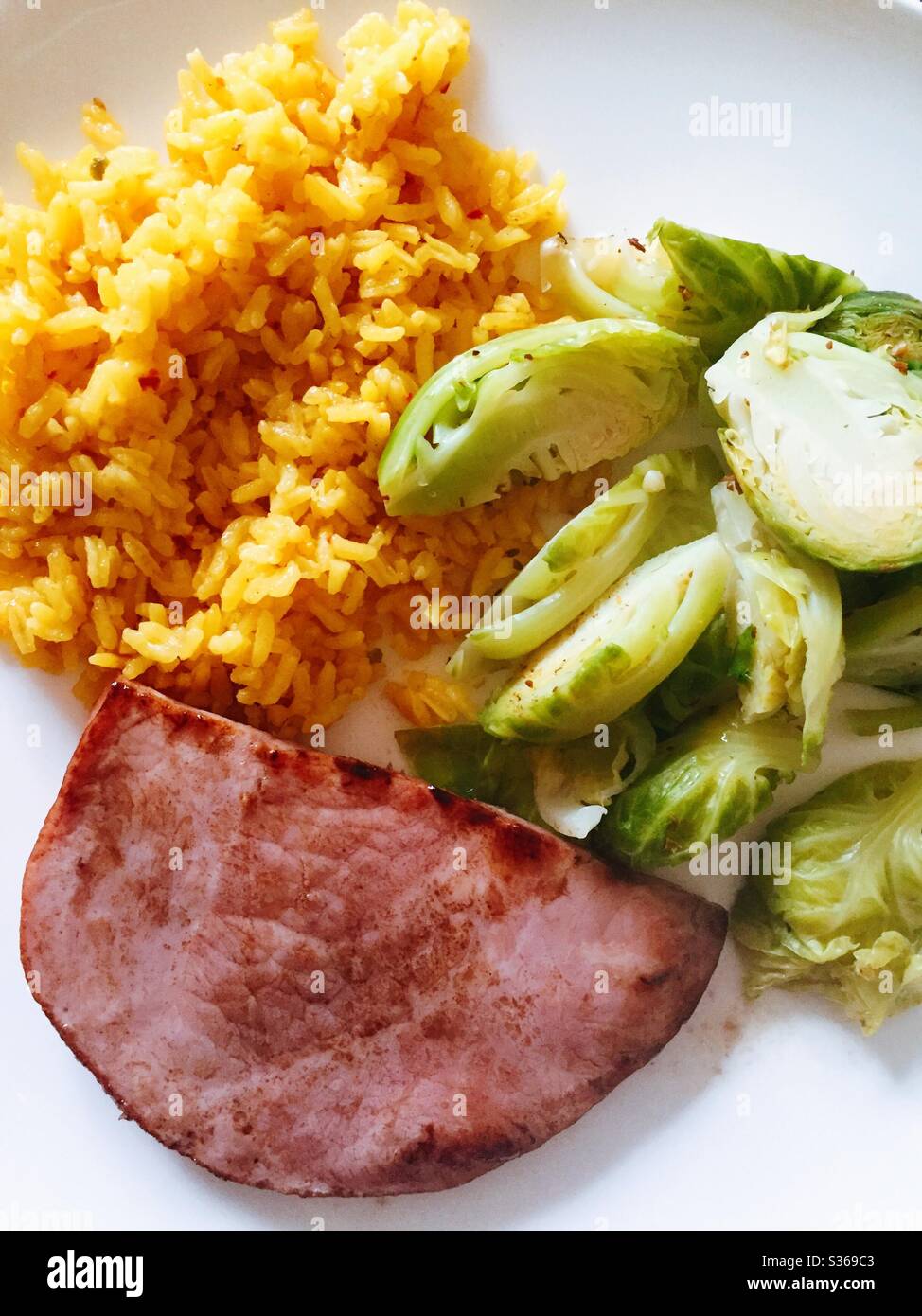 Flat lay of a balanced entrée meal of ham slice, brussels sprouts and ...