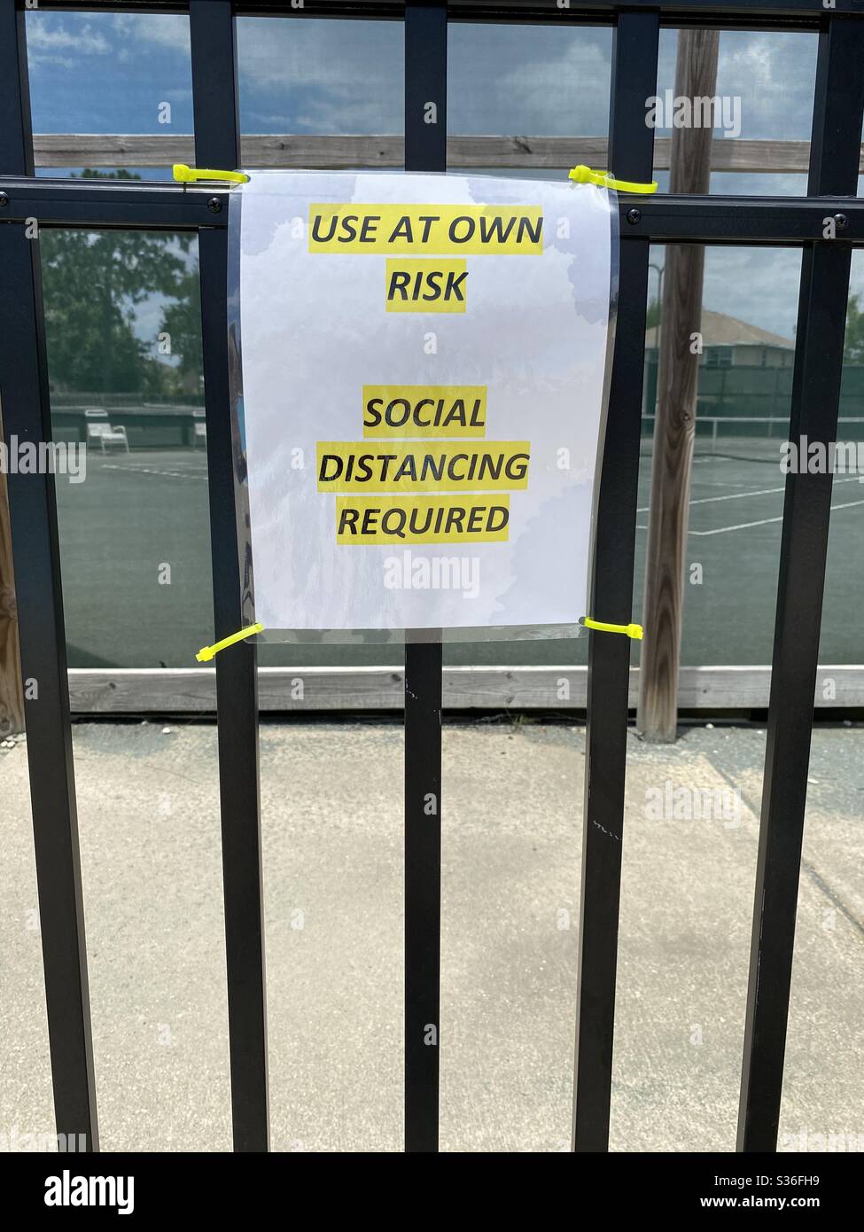 Warning sign at a tennis court use at your own risk due to coronavirus ...