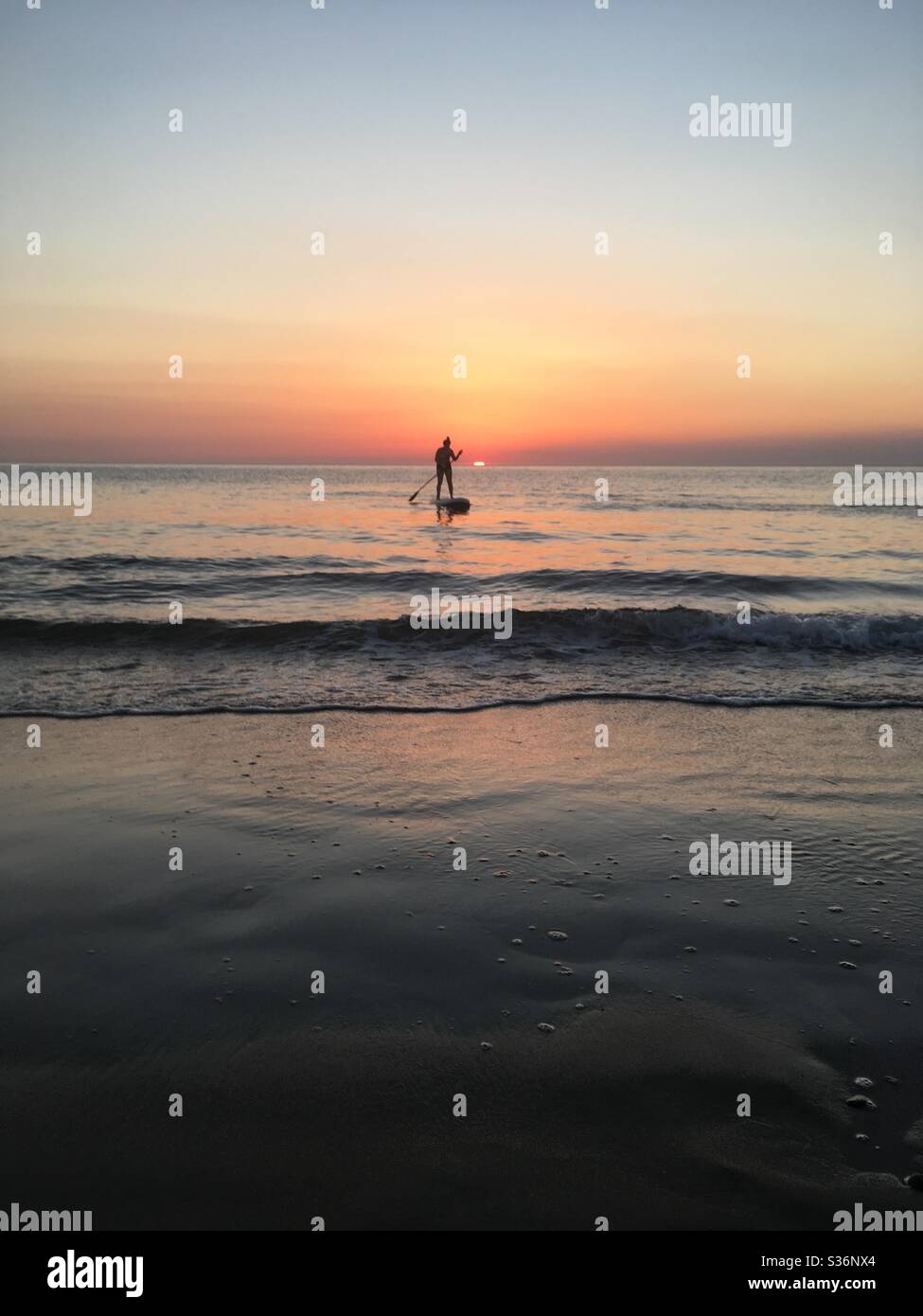 Paddle boarding at sunset Stock Photo - Alamy