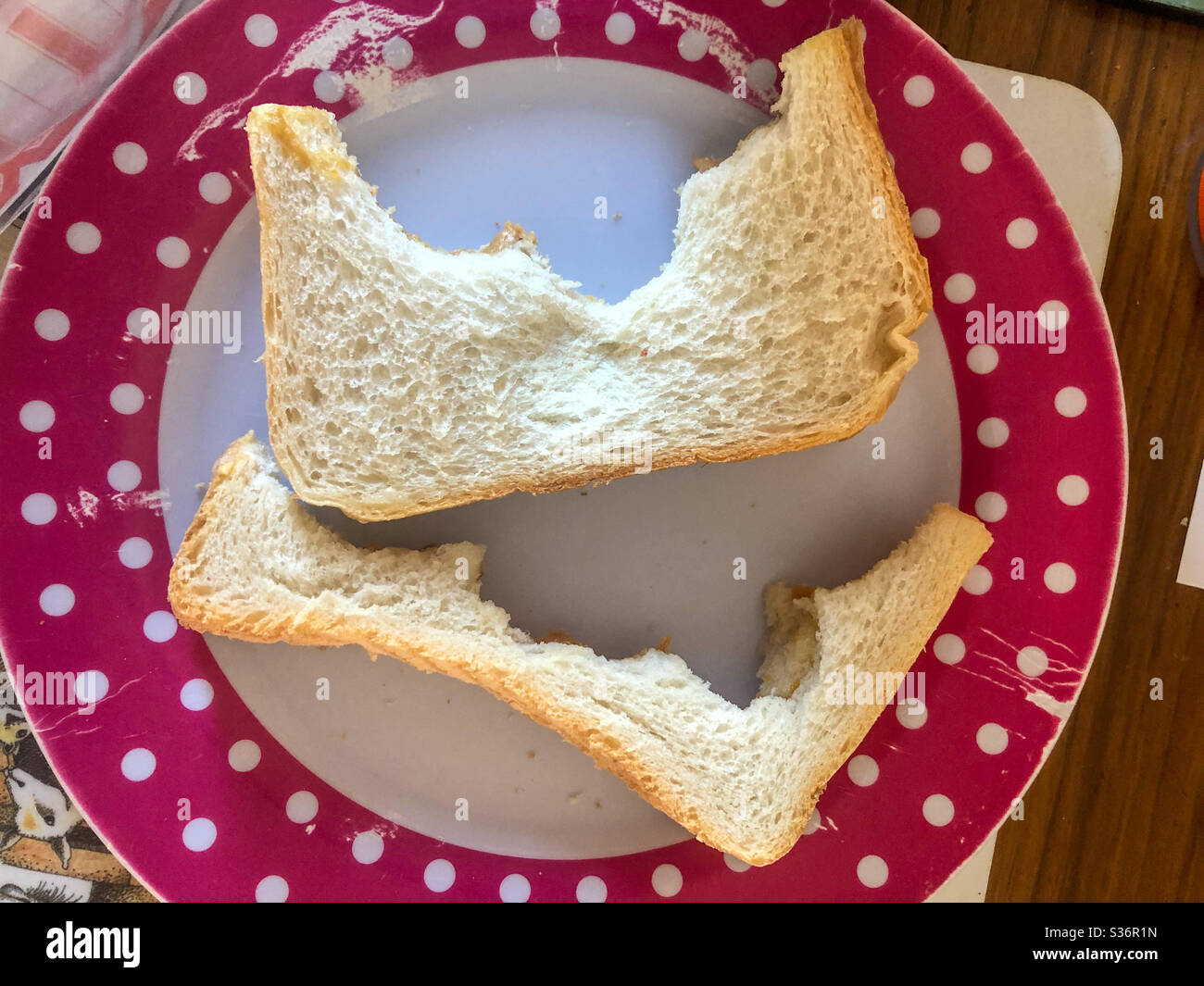 Half eaten sandwiches with the crusts left on the plate. A large bit ...