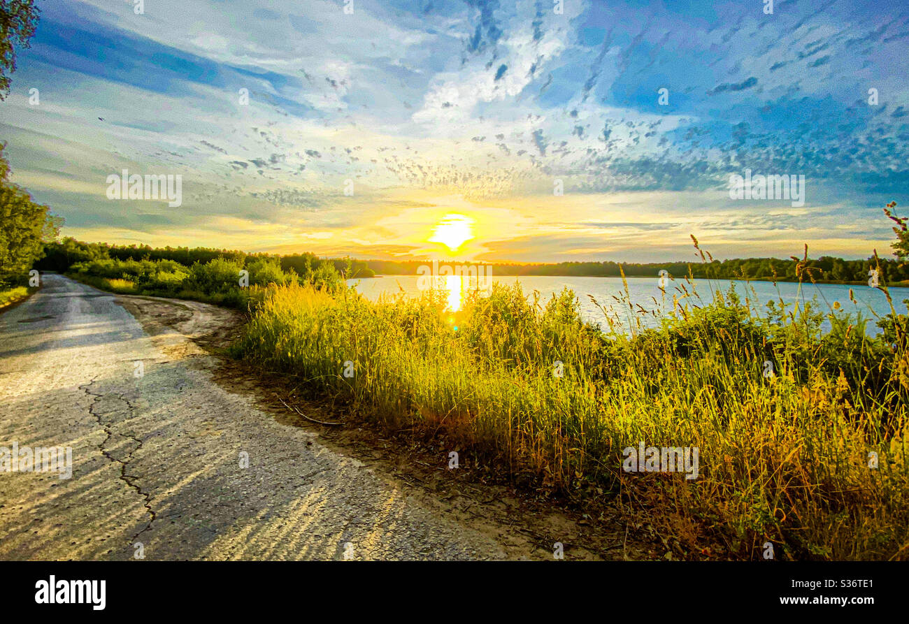 Golden sunrise or sunset sun in a dramatic colorful sky throwing ...