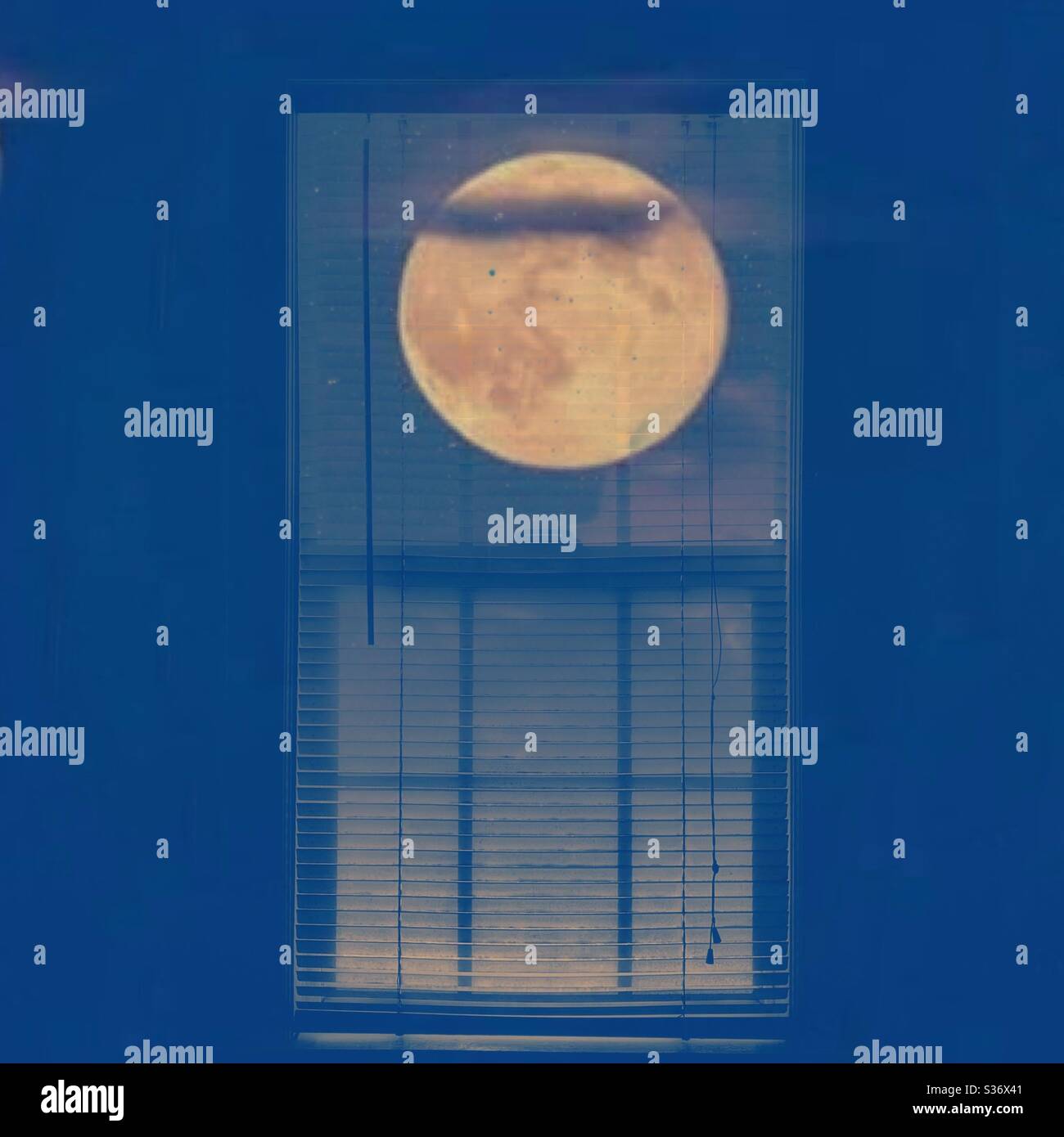 The home window seen a giant yellowish full moon outside at the night ...
