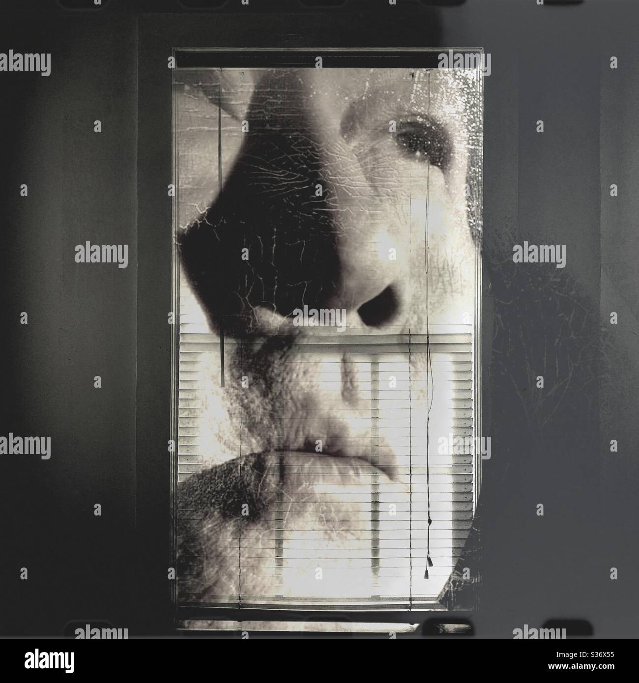 The man’s face in the window at the night set in black and white warm ...