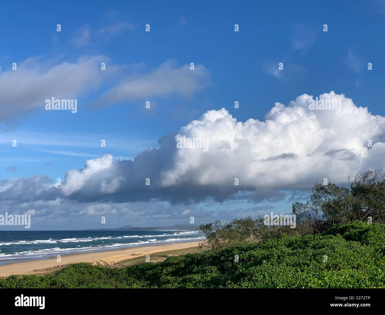Low hanging white cumulus clouds on a blue sky day at the beach Stock ...