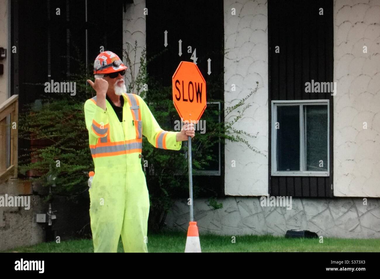 Flag man, directing traffic, Kensington, Alberta, Canada, yellow-green ...