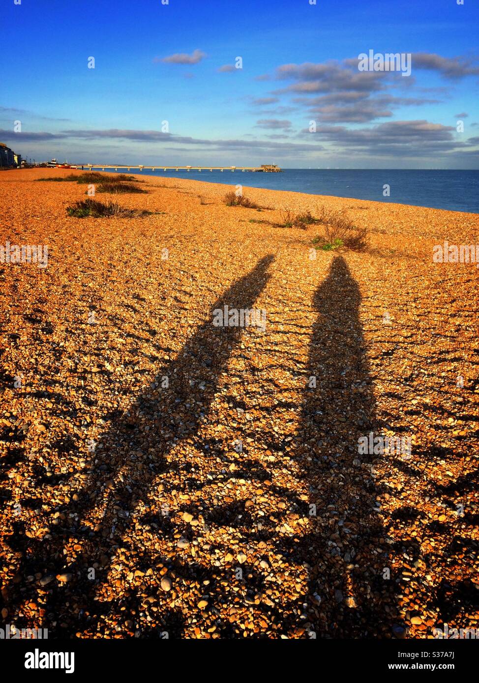 Long shadows of two people on the shingle beach at Deal, Kent, UK Stock ...