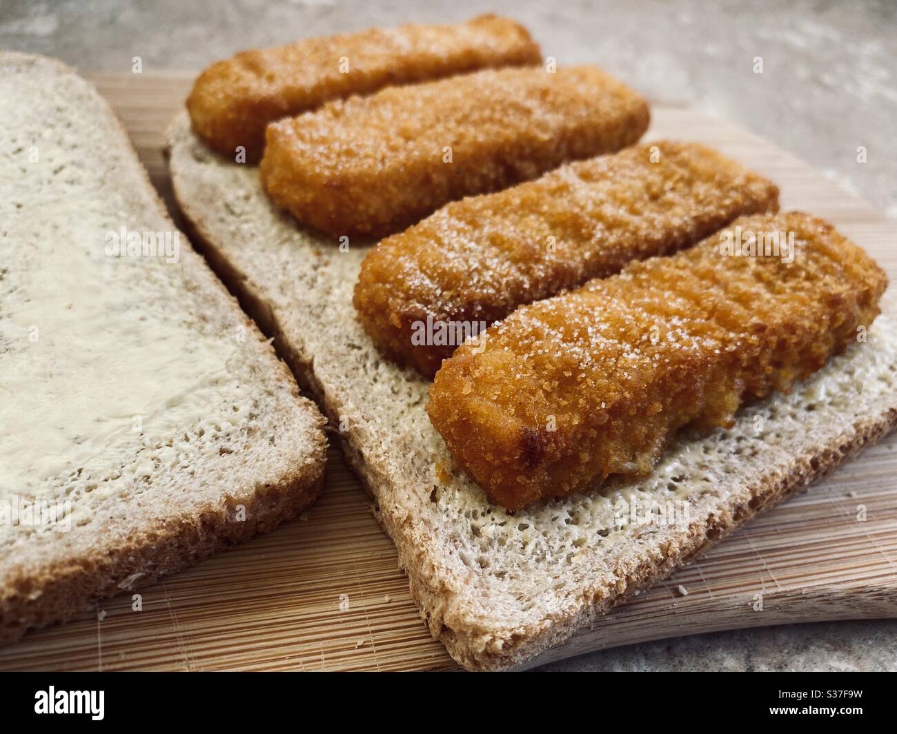 Closeup view of crispy fish fingers covered in salt and vinegar on ...