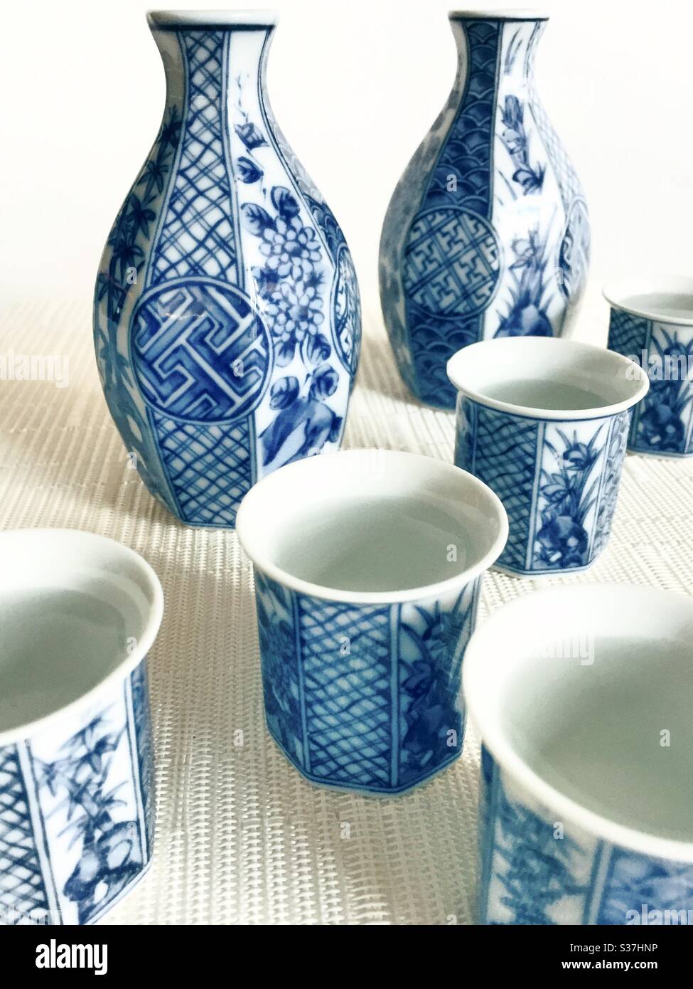 Sake serving set consisting of 5 cups and two bottles on a white ...